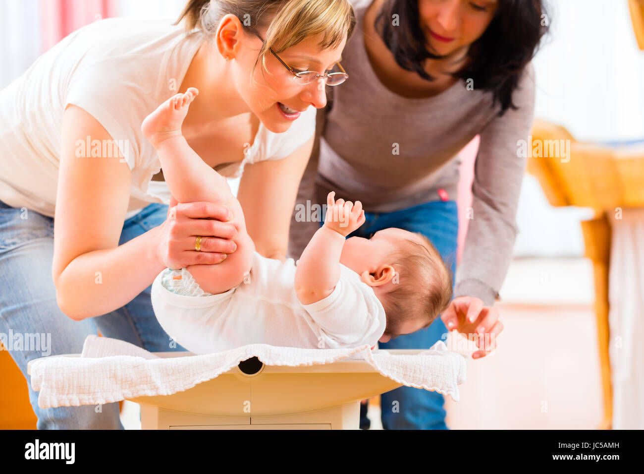Midwife examining newborn baby at postnatal care in practice checking ...