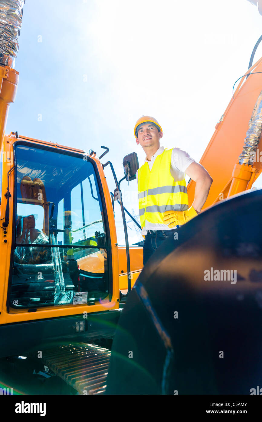 Asian worker standing on construction machinery on building site Stock ...