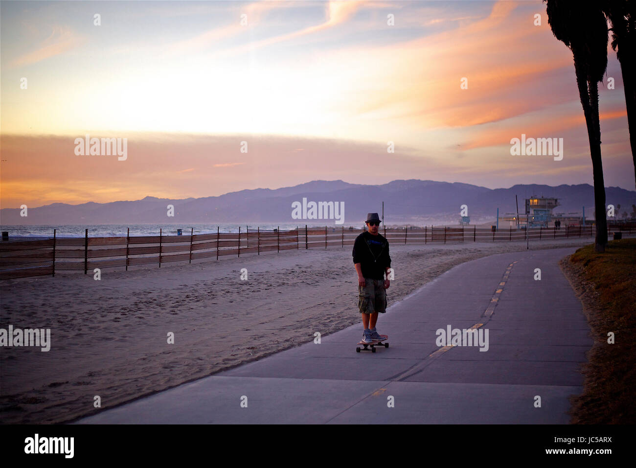 Man riding skateboard on boardwalk near beach, Santa Monica, California ...