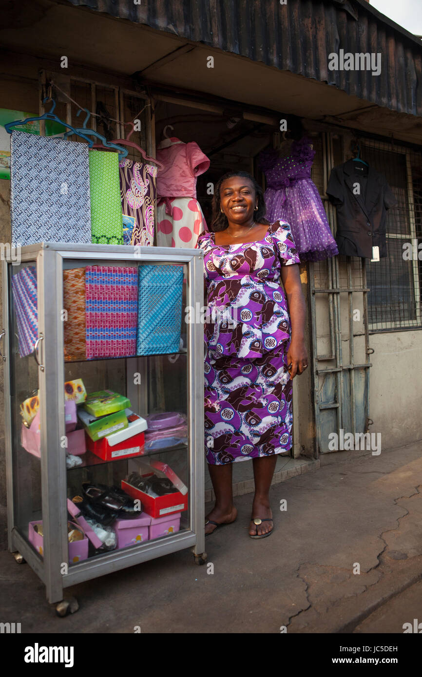 A female shop keeper poses outside her shop with her fabric, Nigeria ...