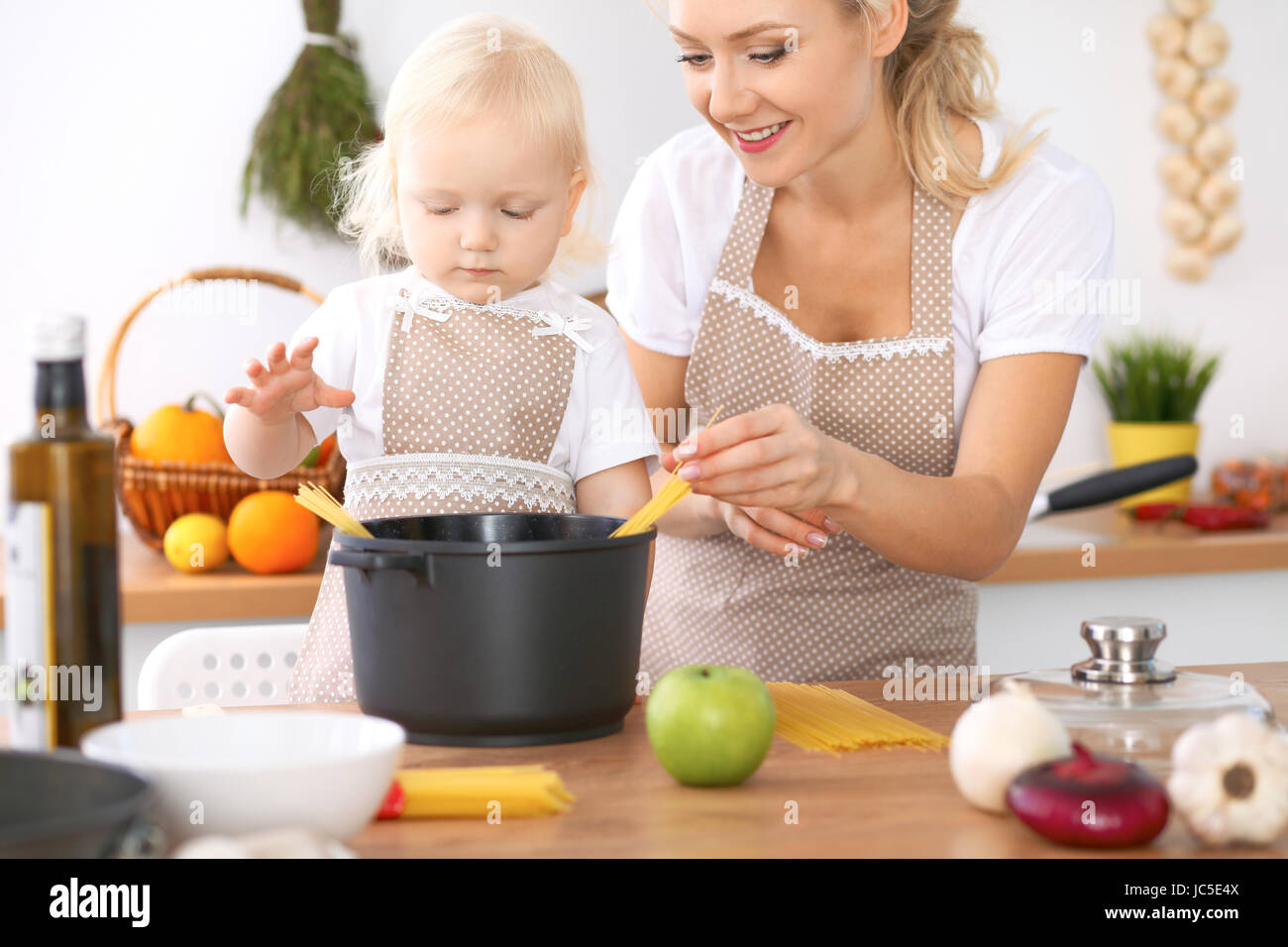 Happy family in the kitchen. Mother and child daughter cooking pasta ...
