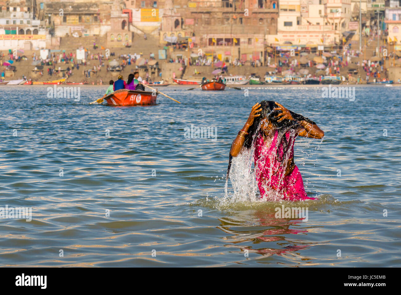 A woman, pilgrim, is taking bath and praying on the sand banks at the ...