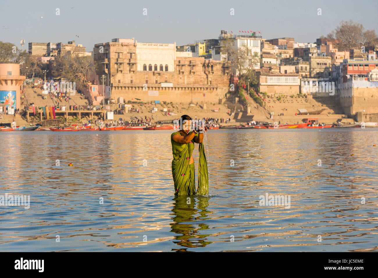 A woman, pilgrim, is taking bath and praying on the sand banks at the ...