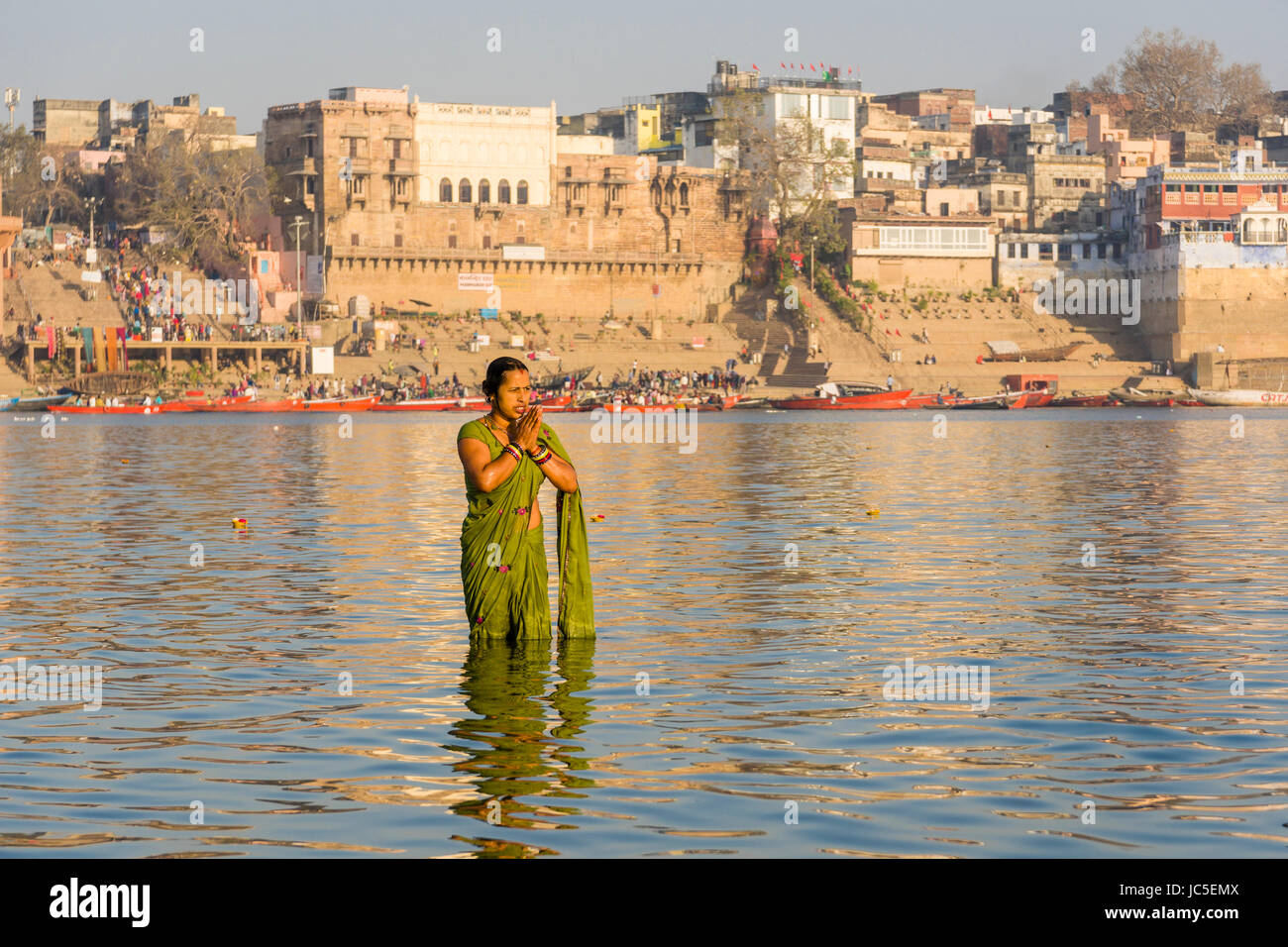 A woman, pilgrim, is taking bath and praying on the sand banks at the ...