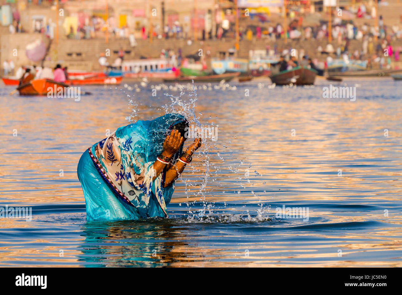 A woman, pilgrim, is taking bath and praying on the sand banks at the ...