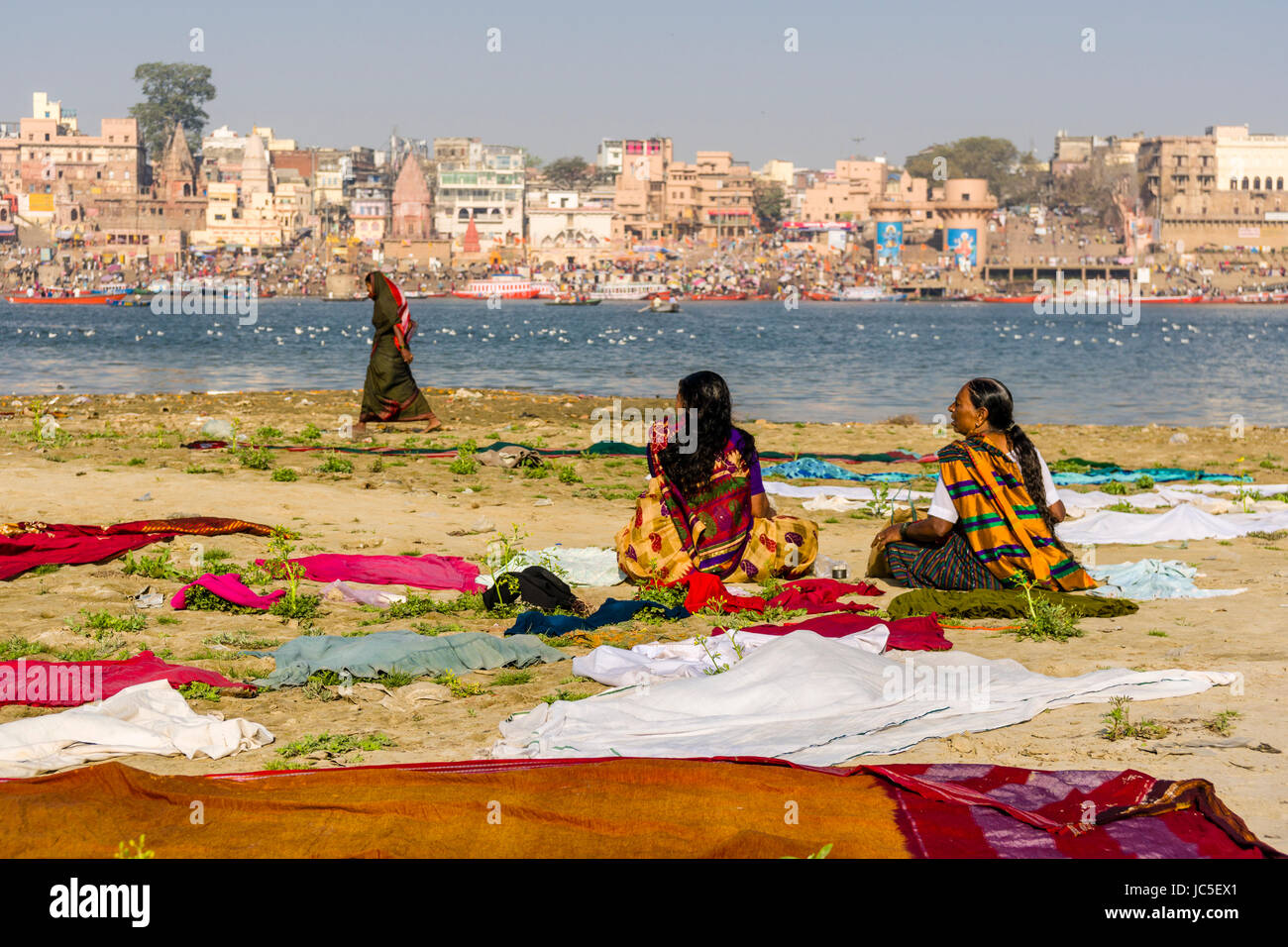 Two women are sitting on the sand banks at the holy river Ganges ...