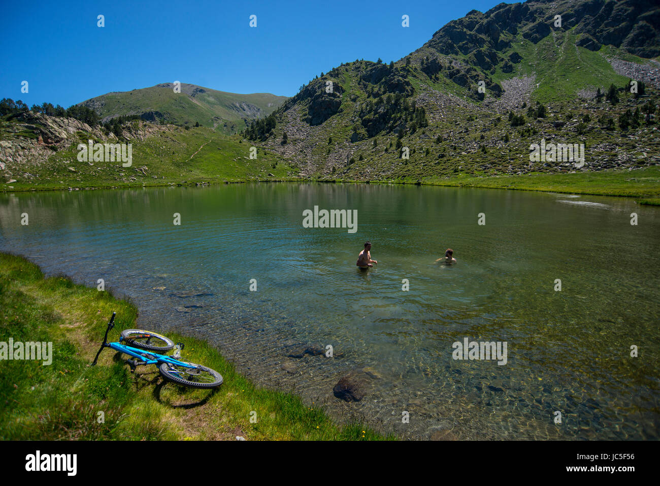 Two mountain bikers swim in a mountain lake in Andorra in the Pyrenees ...
