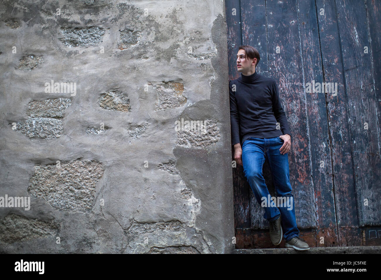A young guy standing near the stone wall Stock Photo - Alamy