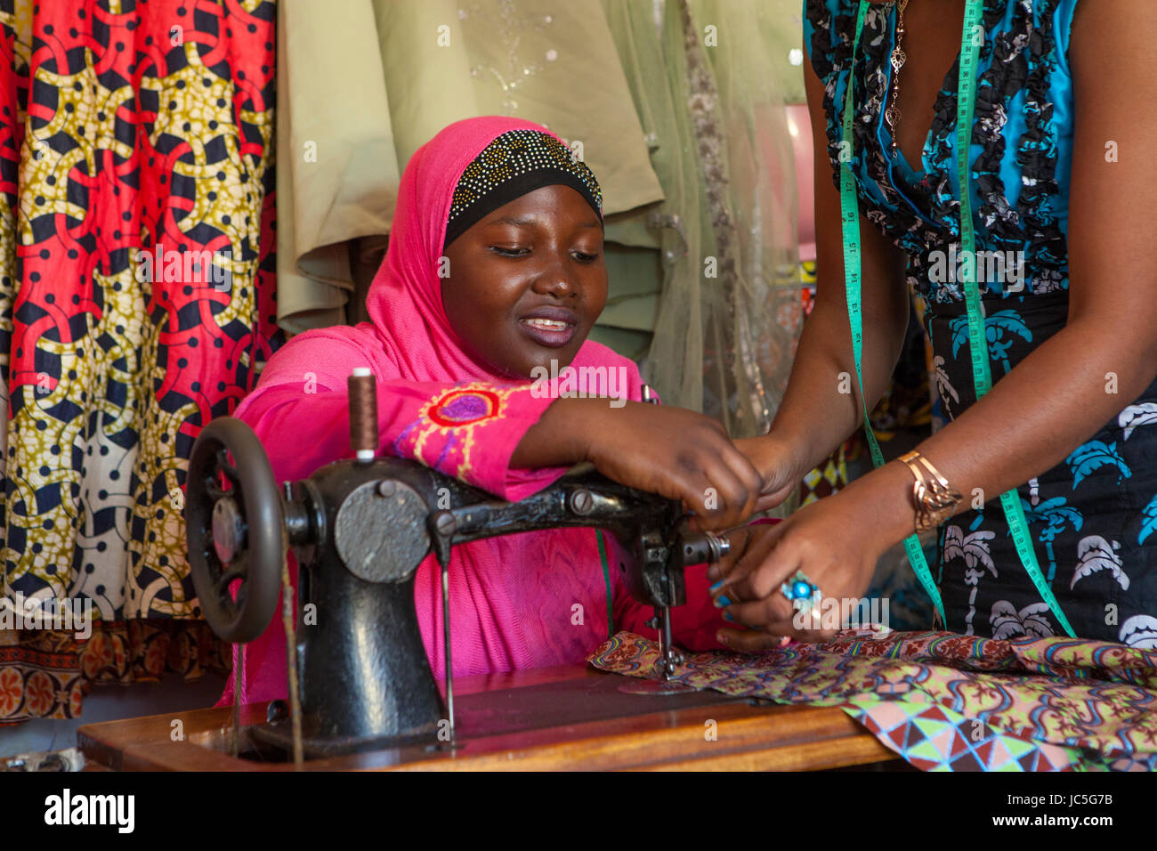 A female tailor teaching sewing techniques to a student, Tanzania ...