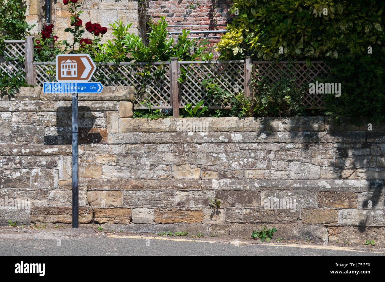 Country House and Cycle Route sign to Tonbridge against a stone wall ...