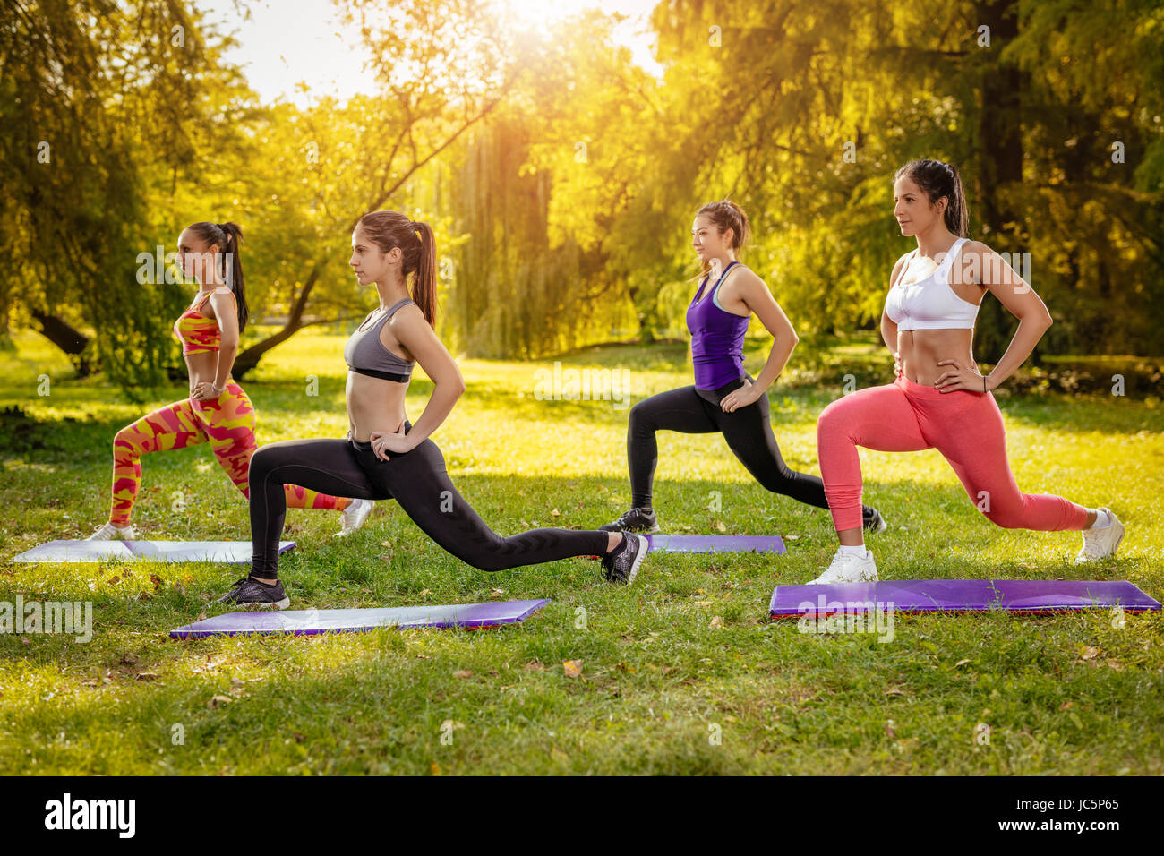 Four beautiful female friends doing exercise in the park Stock Photo ...