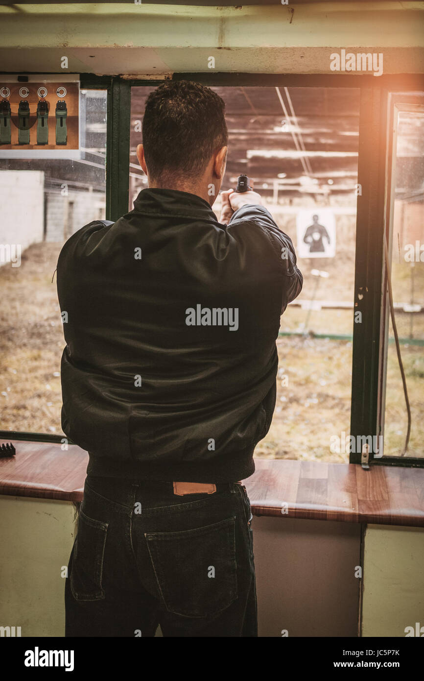 Man firing with pistol on target at the shooting range. Rear view Stock ...
