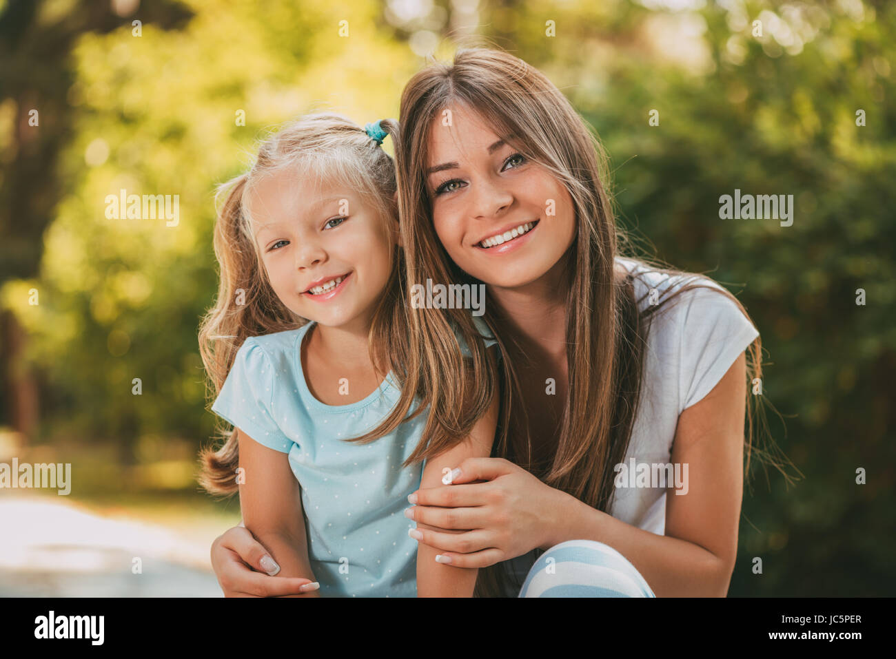 Beautiful Mother And Daughter Posing At The Park In Spring Day Looking