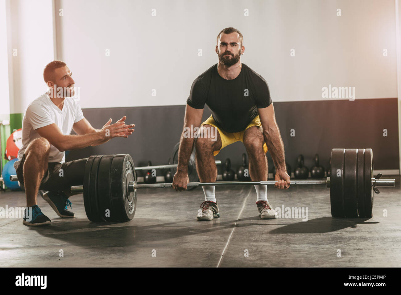 Young man doing crossfit workout with a personal trainer Stock Photo ...