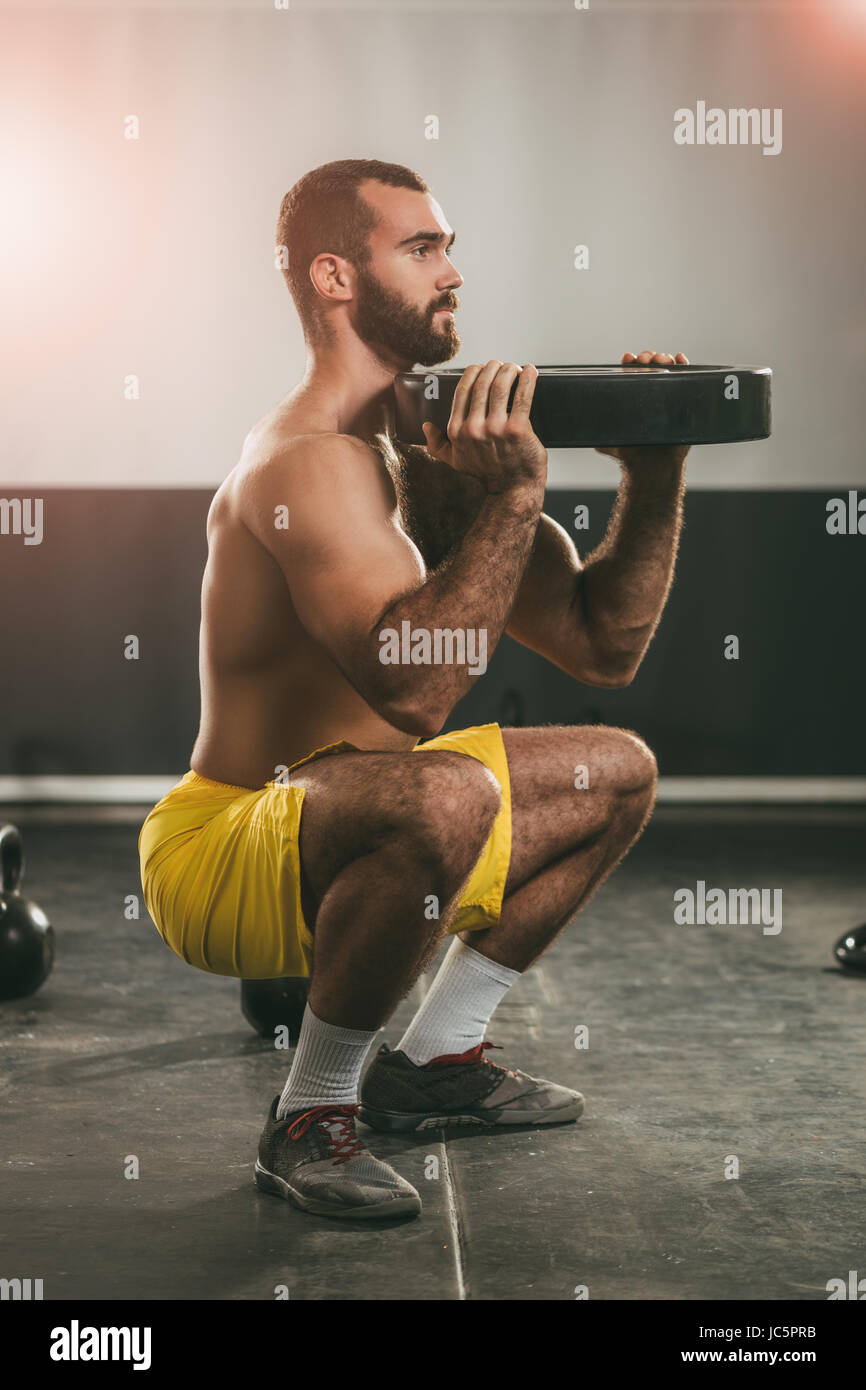 Young muscular man doing squats exercise with dumbbell. Strong male ...