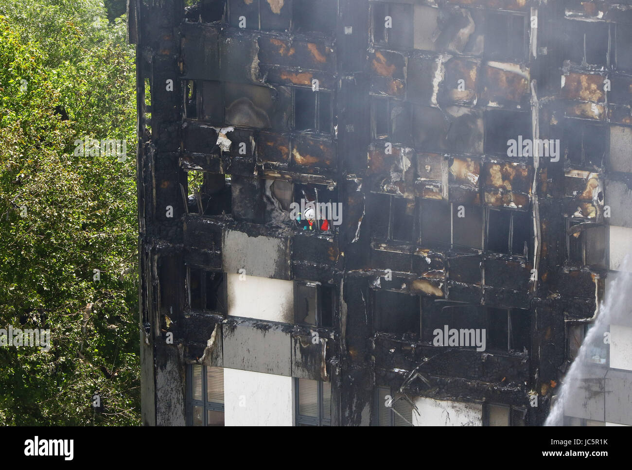 A firefighter photographs damage after a fire engulfed the 24-storey ...