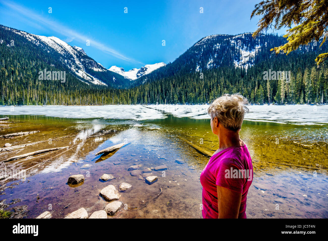 Woman enjoying the view of the partly frozen Lower Joffre Lake and the ...