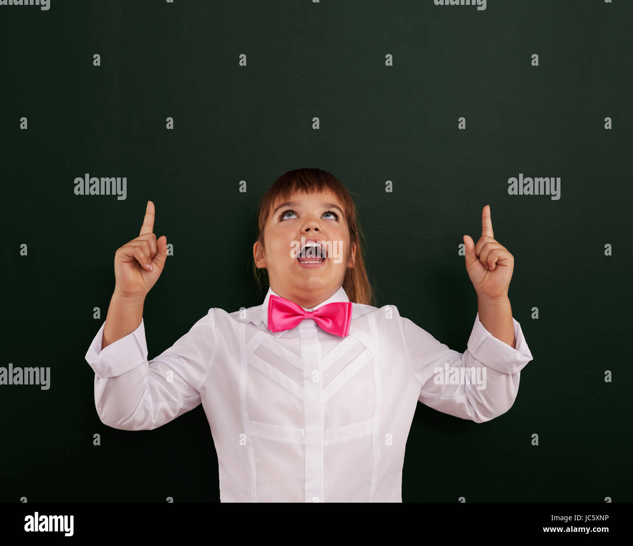 Smiling girl with pink bow tie pointing above her head Stock Photo - Alamy