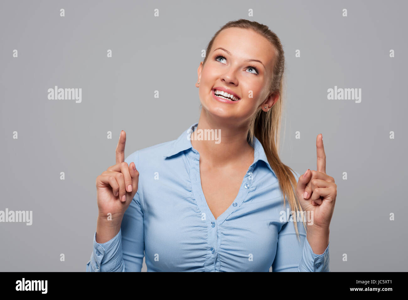 Smiling and beautiful woman showing on copy space above her Stock Photo ...