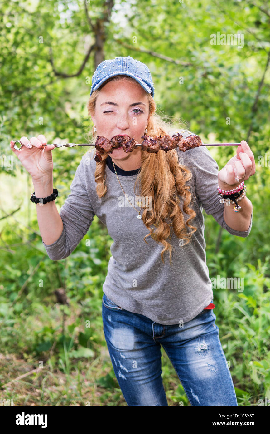 Woman eats meat and winks Stock Photo - Alamy