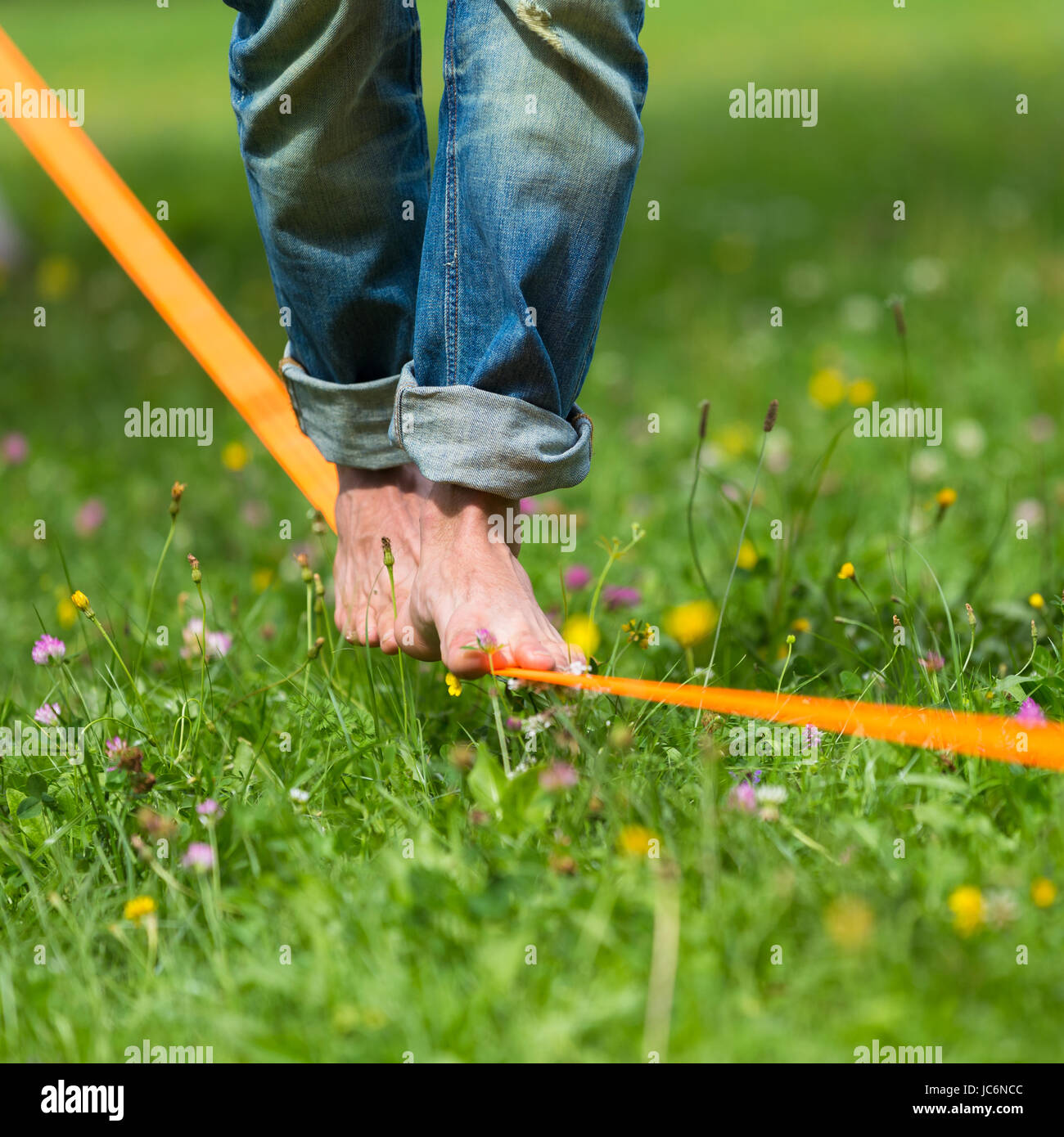 Guy practising slack line in the city park. Slacklining is a practice ...