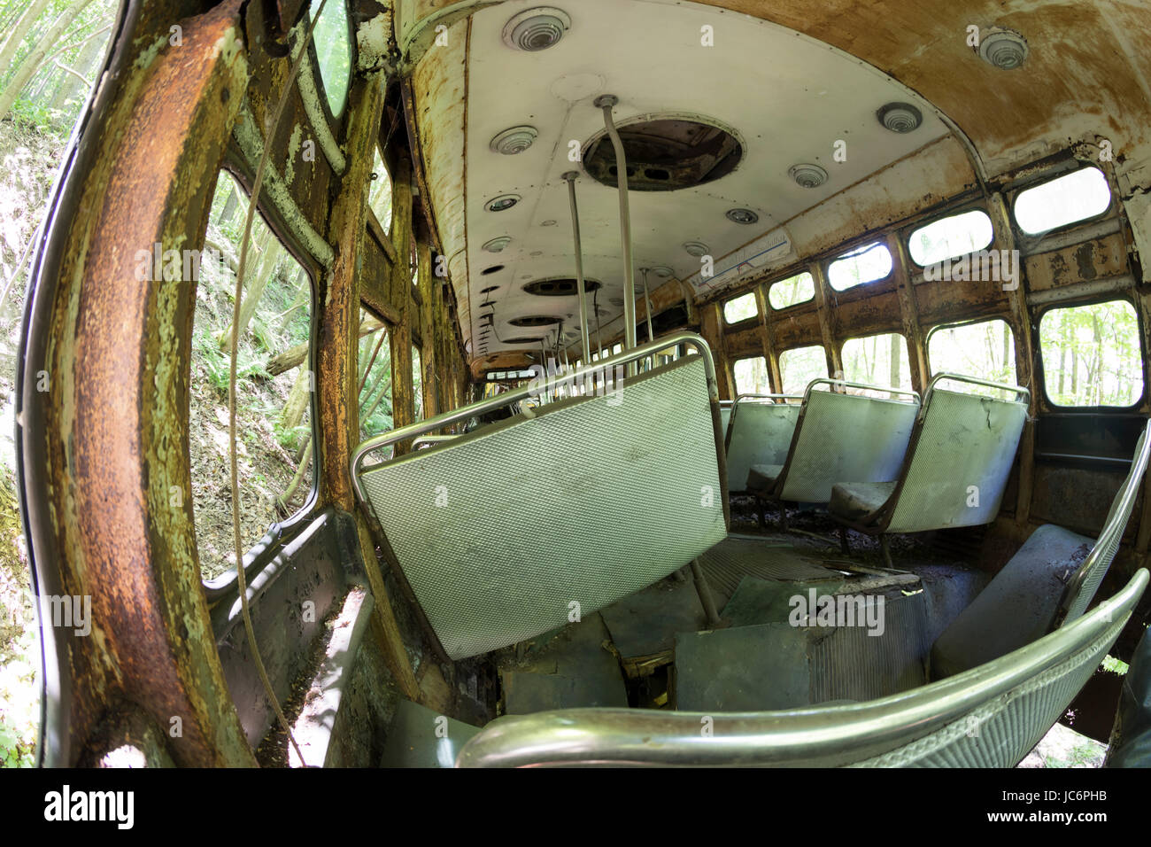 Rusting interior of abandoned trolley car with metal seats in woods ...