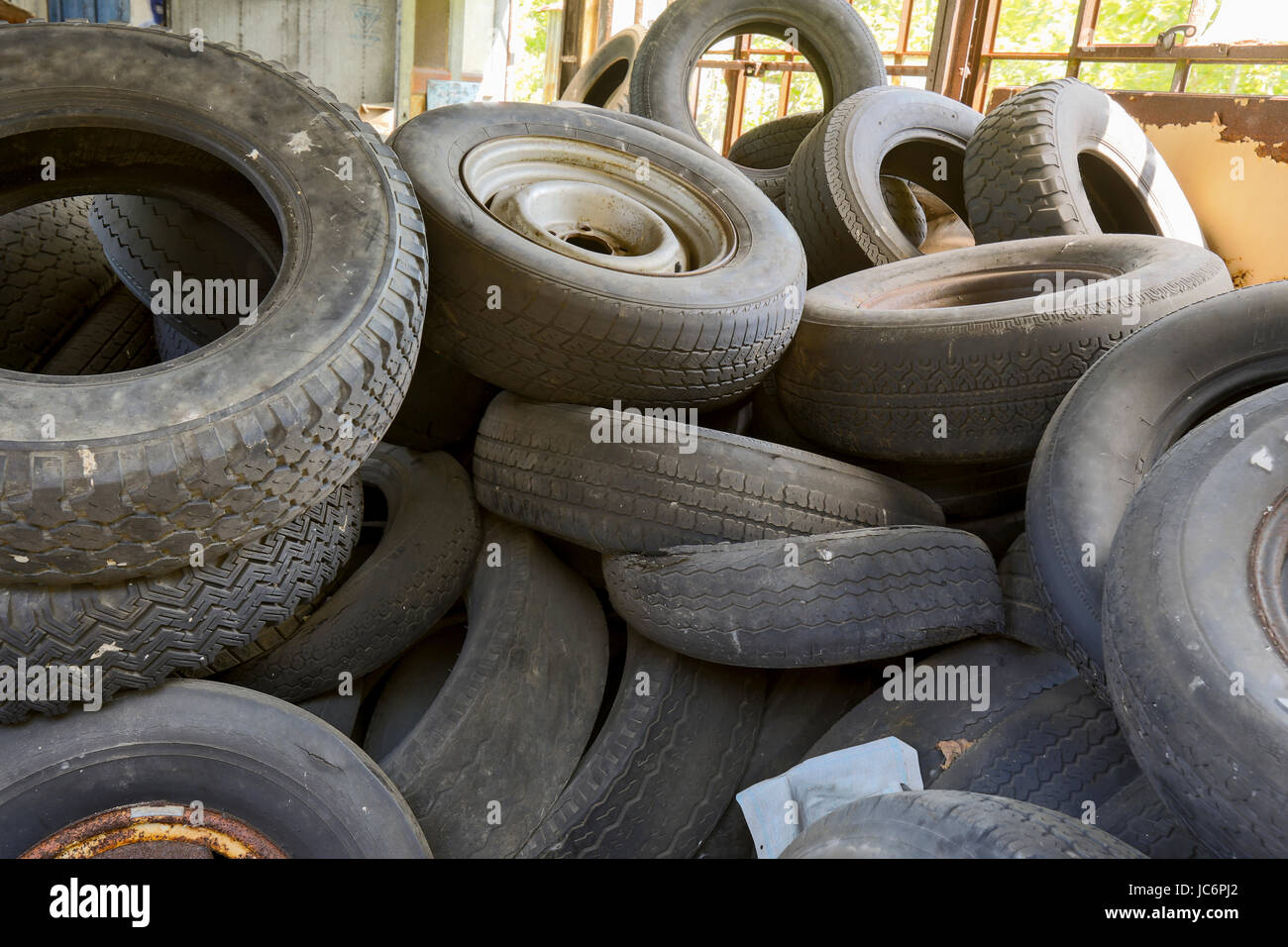 Pile of old tires and rusty rims piled inside shed Stock Photo - Alamy