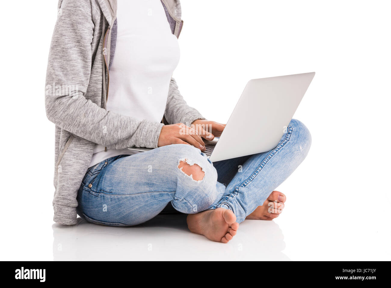 Young female student sitting with crossed legs working with a laptop ...