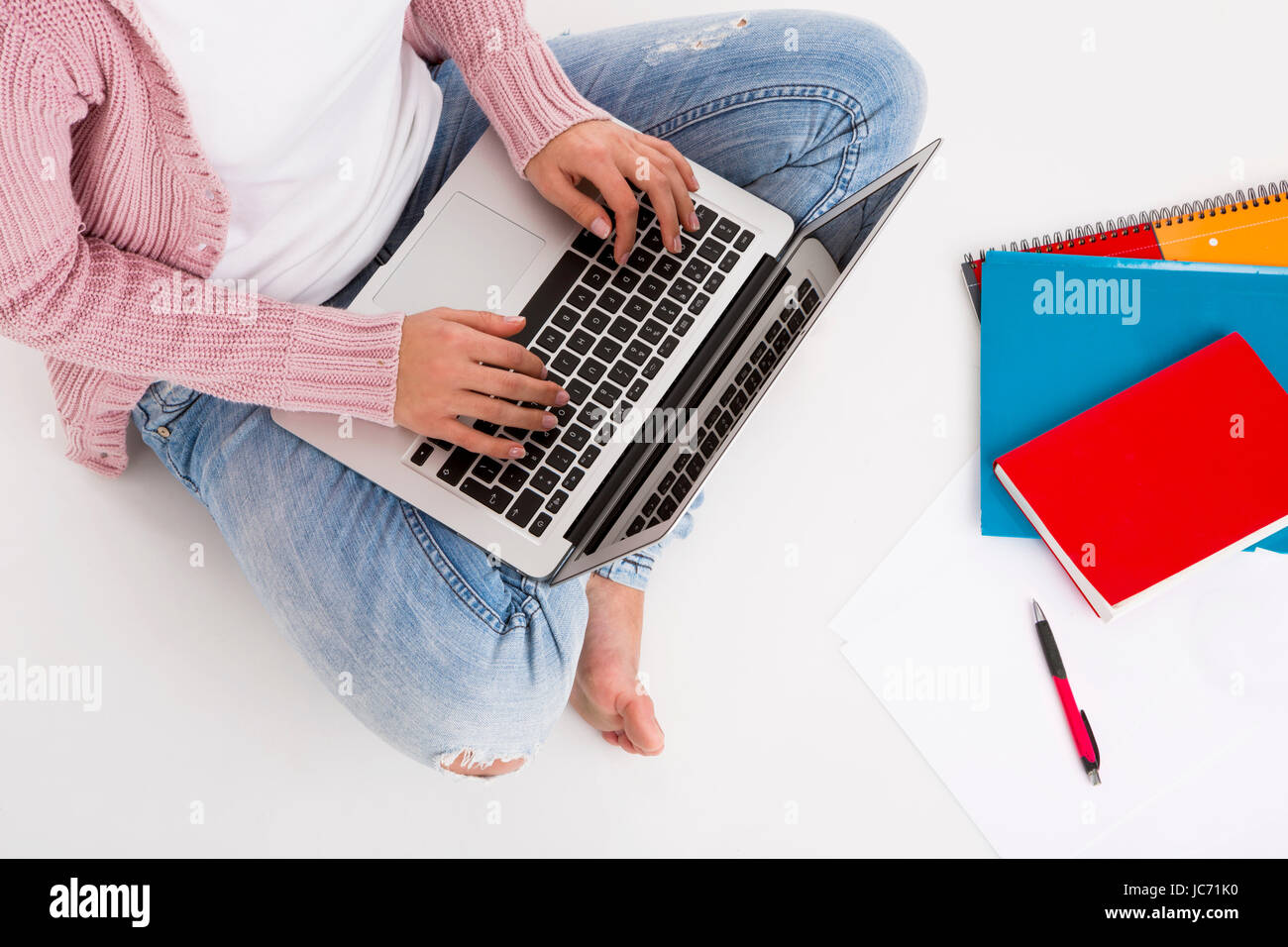 Young female student sitting with crossed legs working with a laptop ...