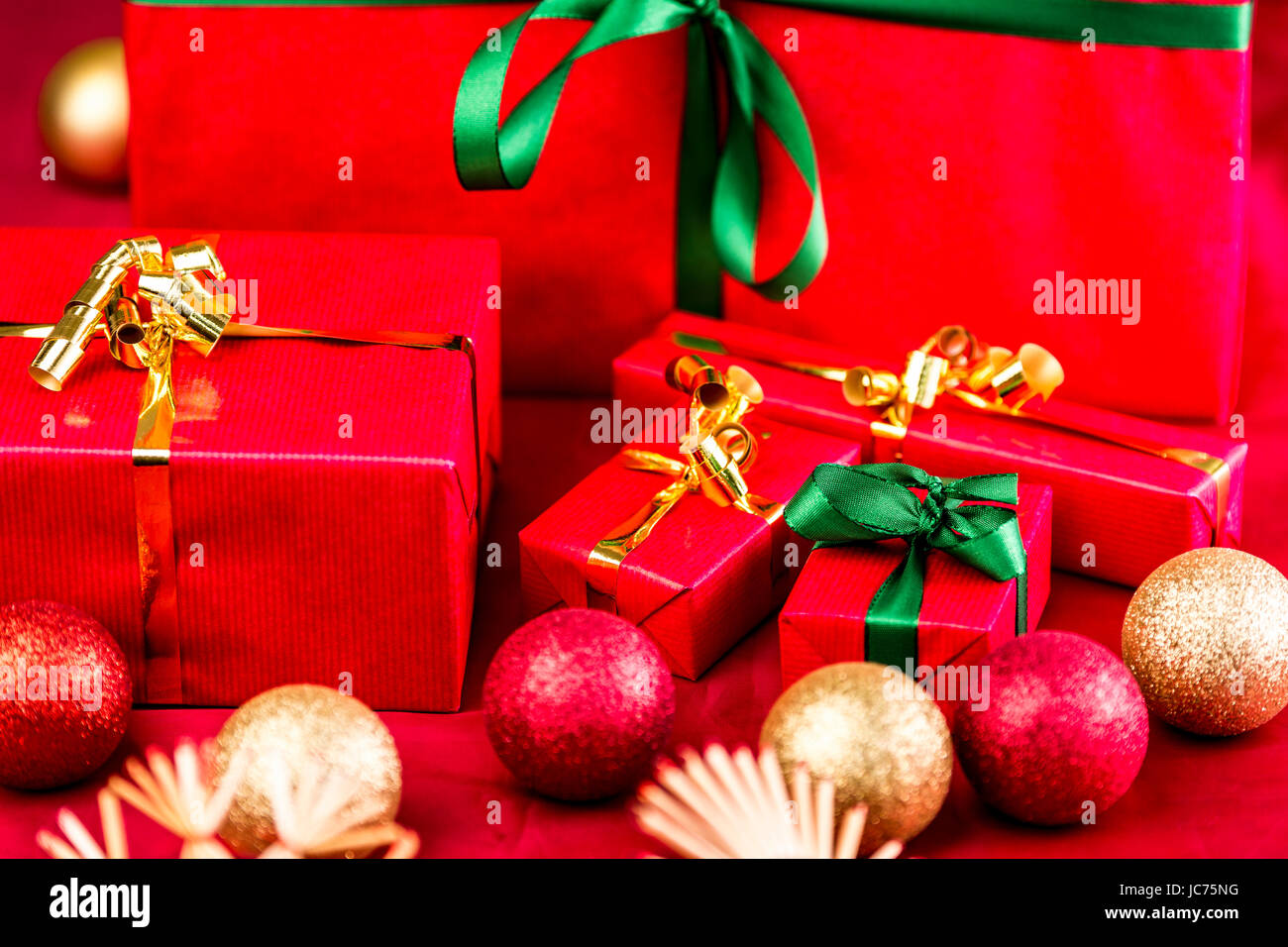 Five red Christmas presents placed on a red cloth. Bows in green and ...