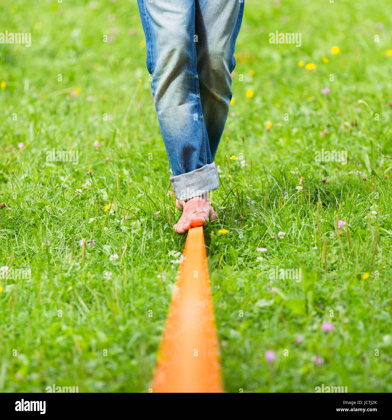 Guy practising slack line in the city park. Slacklining is a practice ...