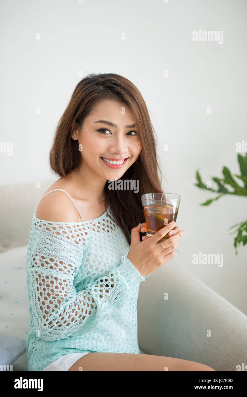 Beautiful young asian woman drinking her morning tea over a breakfast ...