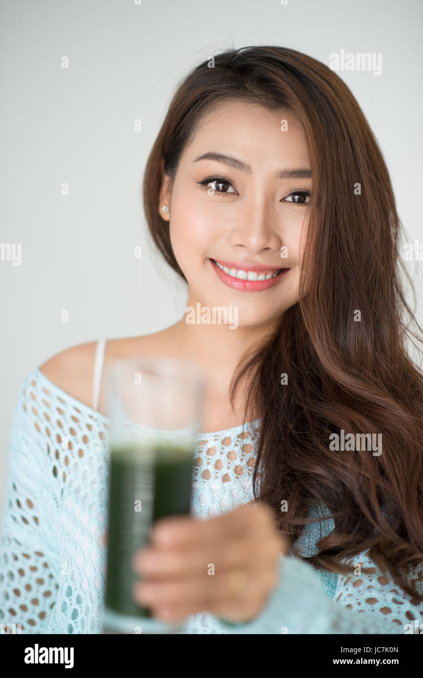 Pretty Young Asian Woman Drinking Green Fresh Vegetable Juice Or