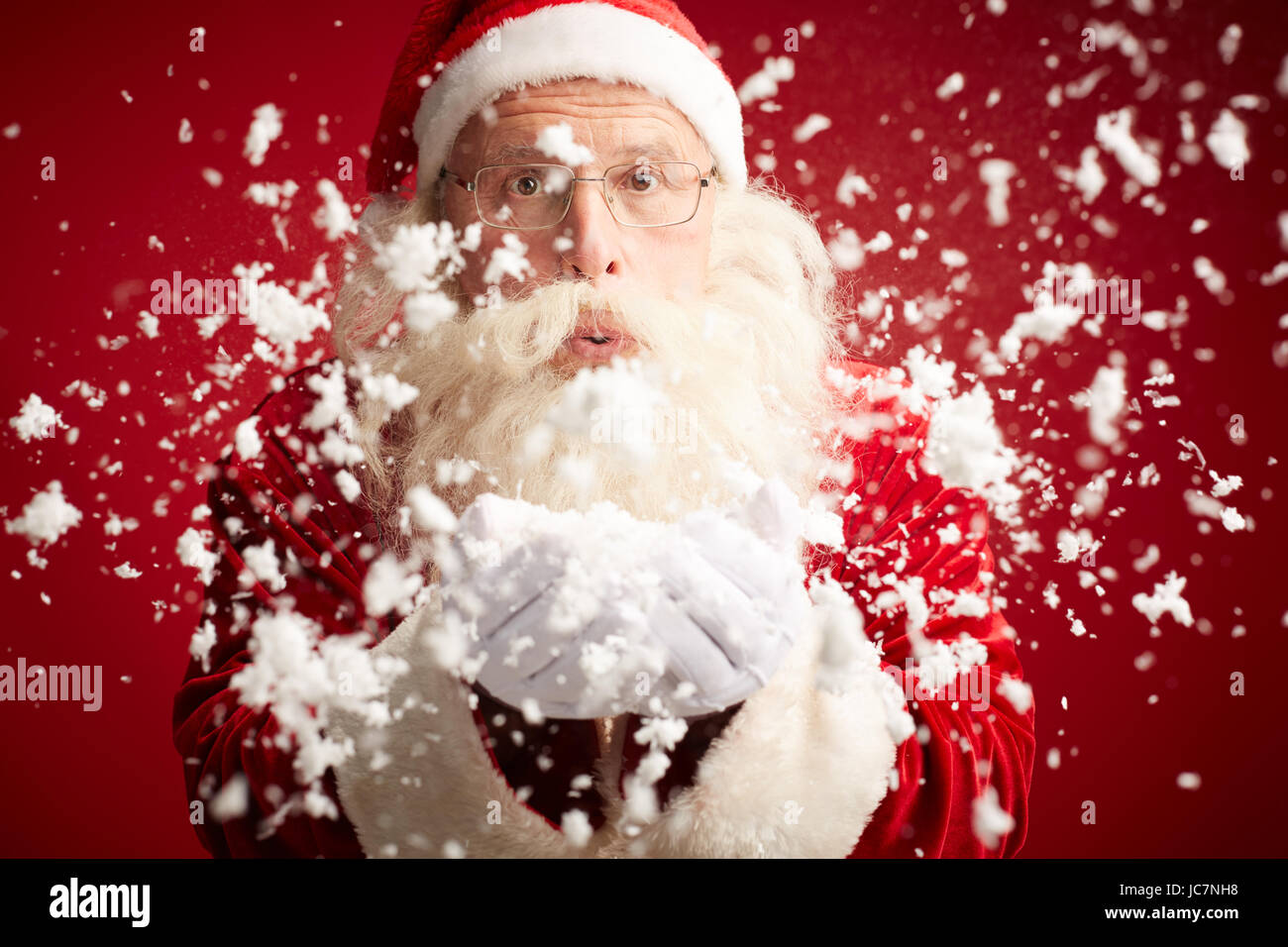 Santa Claus blowing snow and looking at camera Stock Photo - Alamy