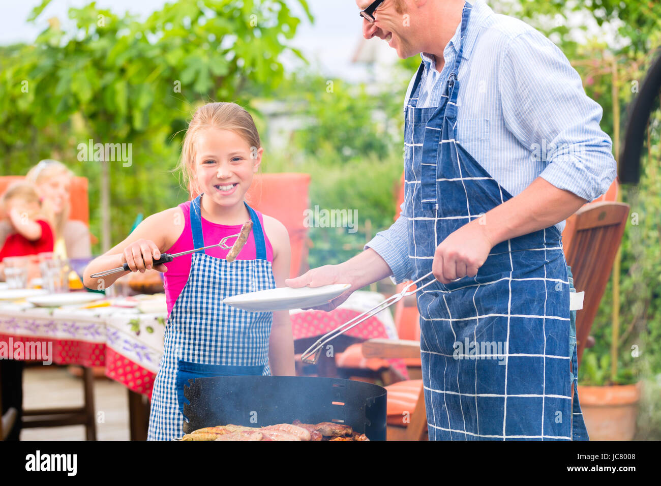 Father and daughter making barbecue in the garden in summer with ...