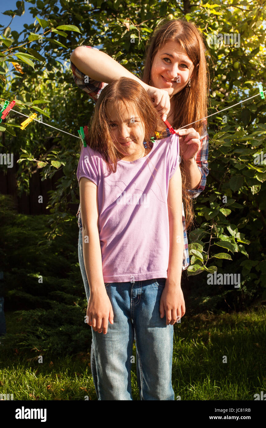 Brunette woman hanging girl on clothesline at garden Stock Photo - Alamy
