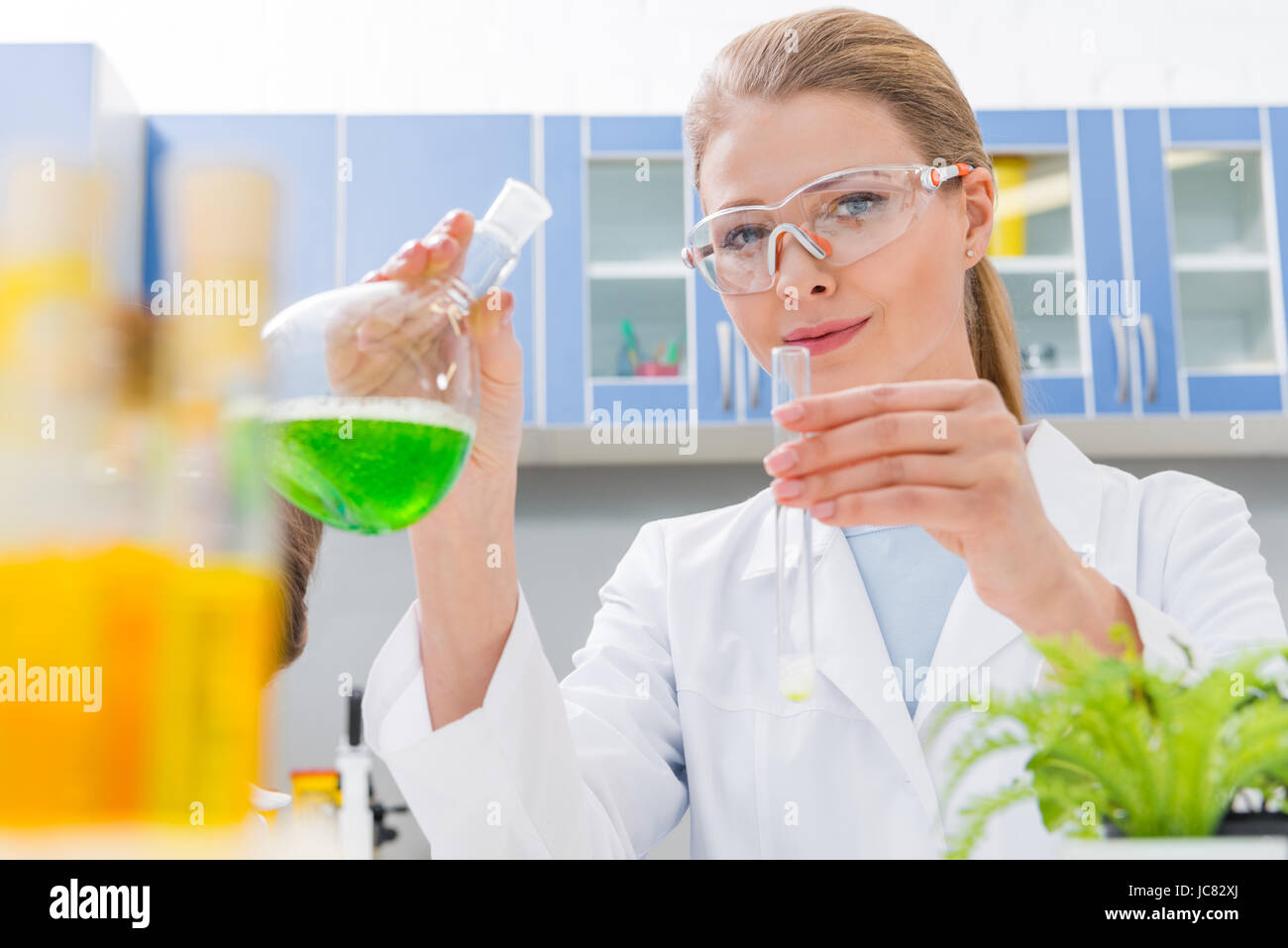 Smiling professional scientist in protective glasses making experiment ...