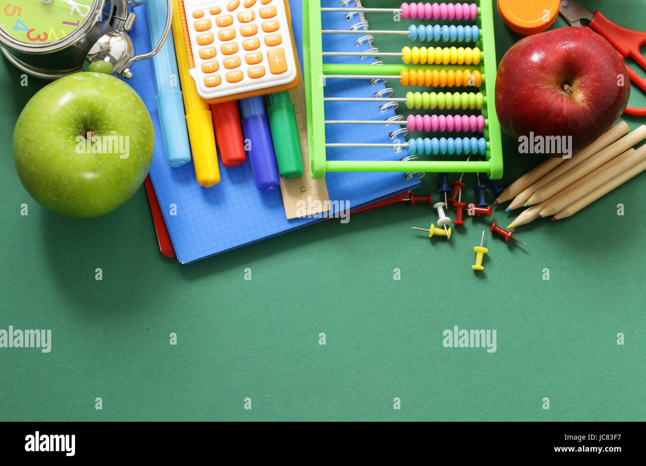 School supplies and apple on a green background Stock Photo - Alamy
