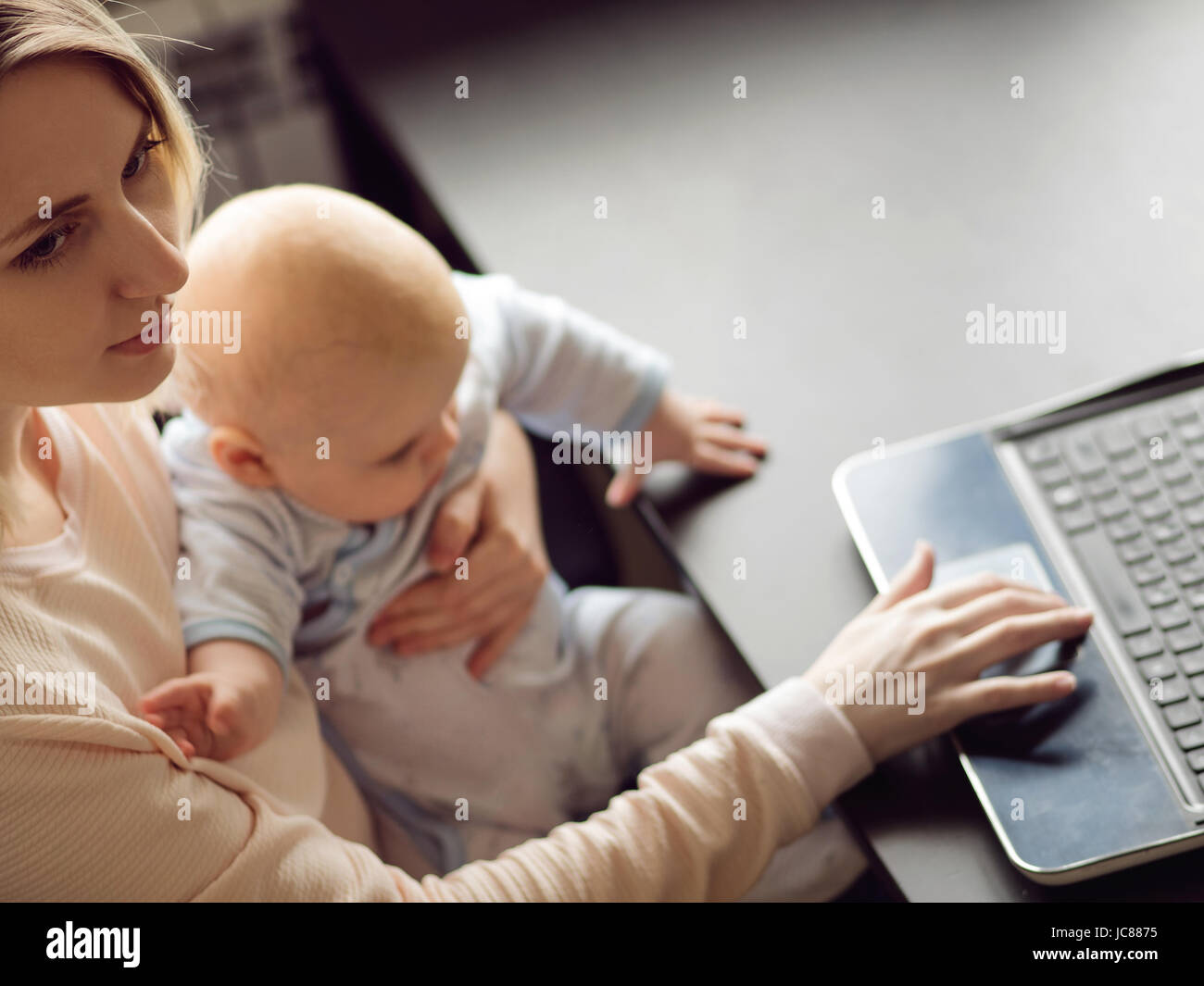 Young mother in home office with computer and her baby. Work and child ...