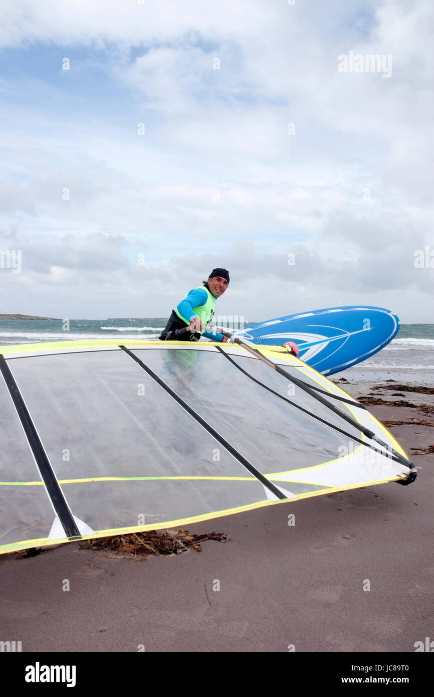 windsurfer getting equipment ready on the beach in the maharees county ...