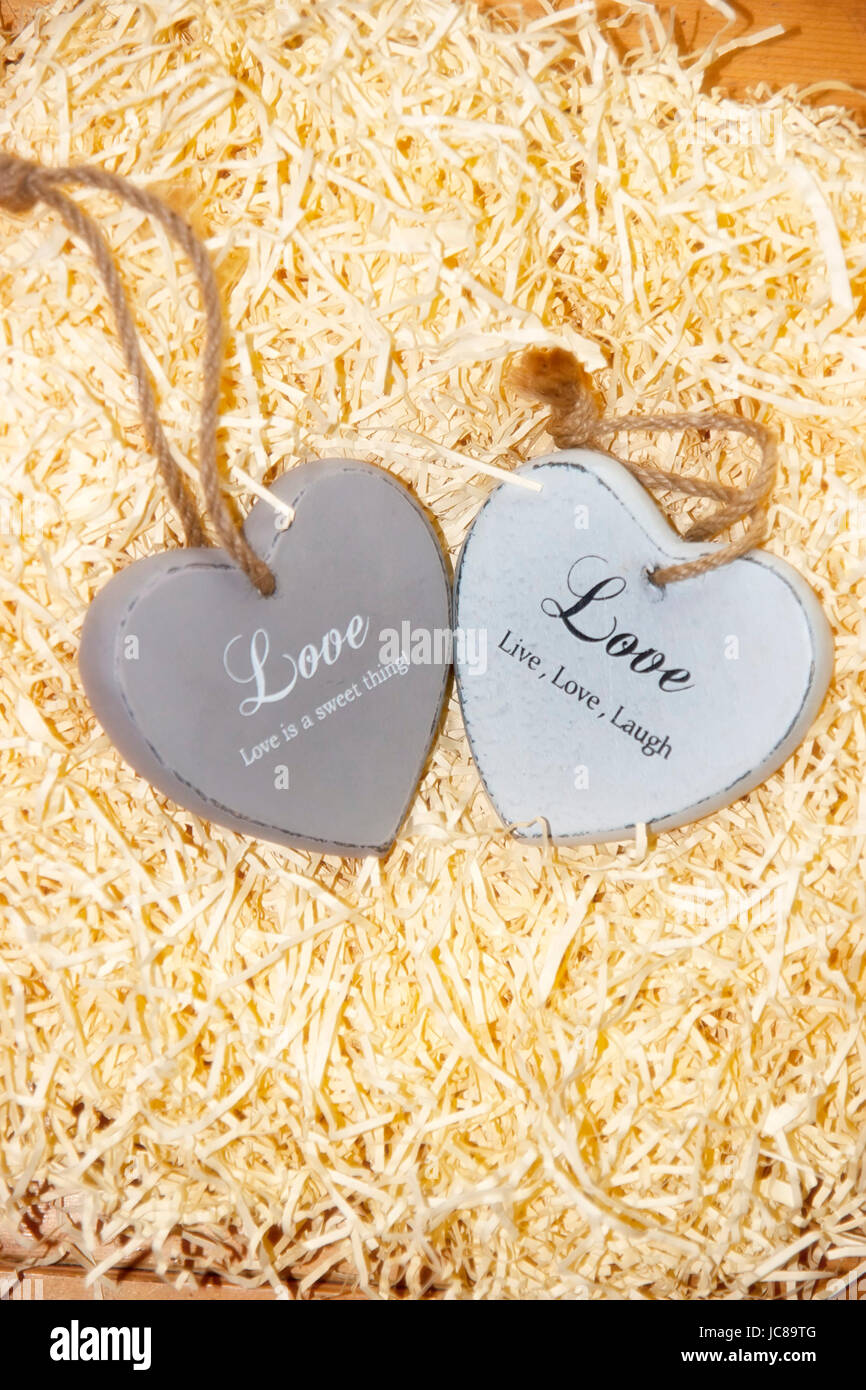 two grey wooden love hearts in a love nest made of straw with loving ...