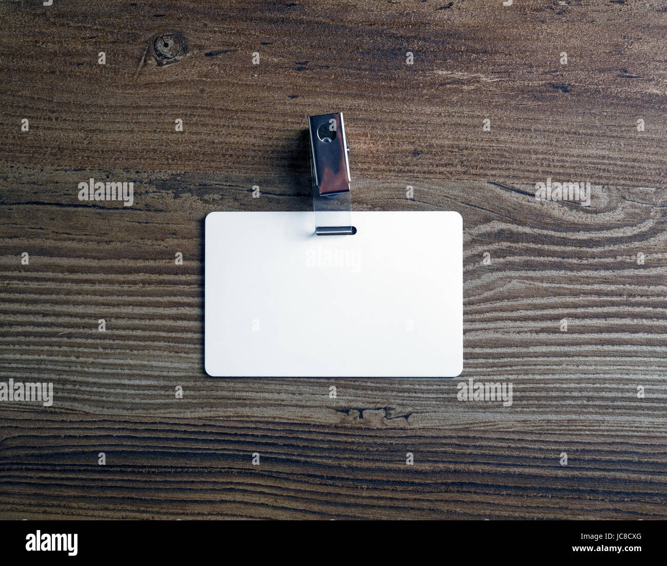Photo of blank white plastic badge on vintage wooden table background ...