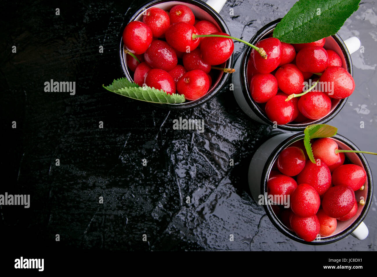 Cherry in enamel cup on black background. Healthy, summer fruit ...