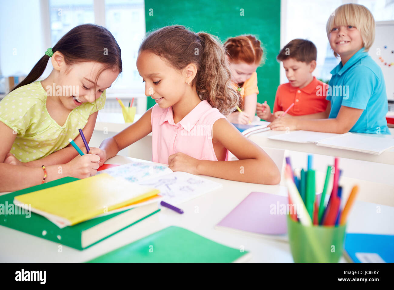 Two schoolgirls drawing in group on background of classmates Stock ...