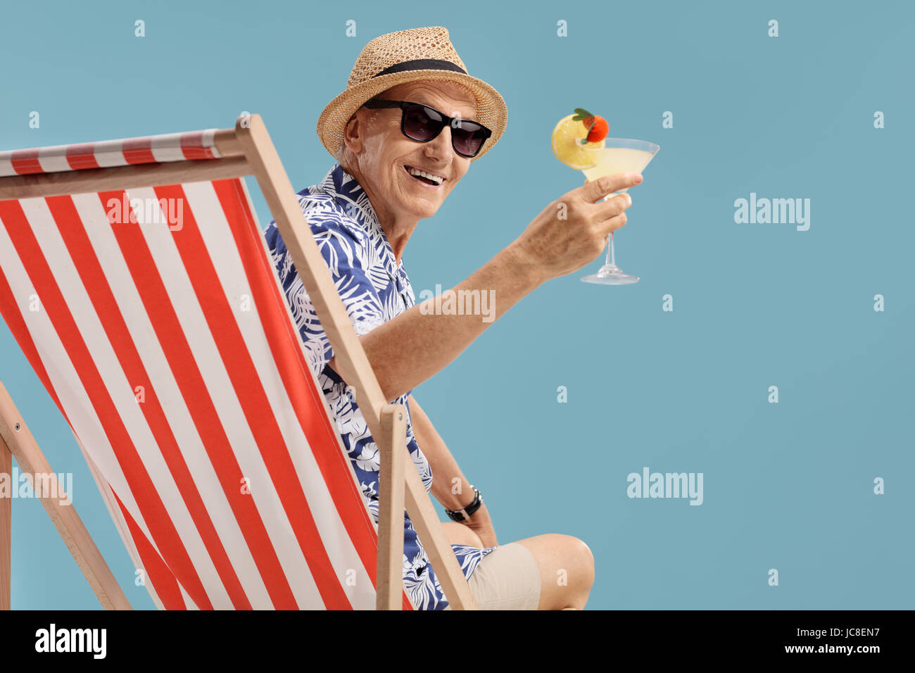 Mature tourist with a cocktail sitting on a sun lounger isolated on ...