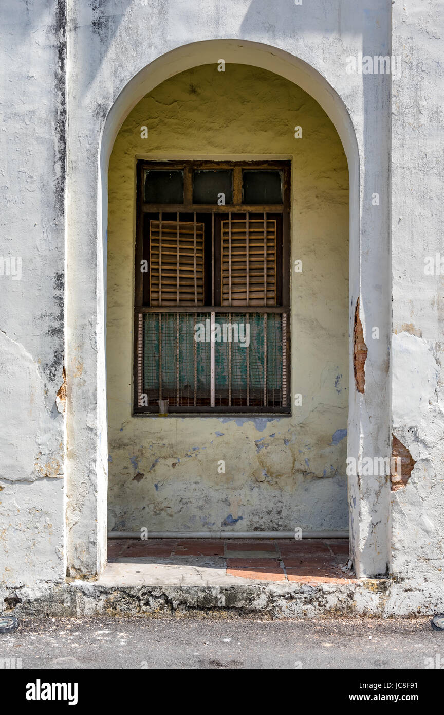 arched faced with old crumbling white wall and inset barred window ...