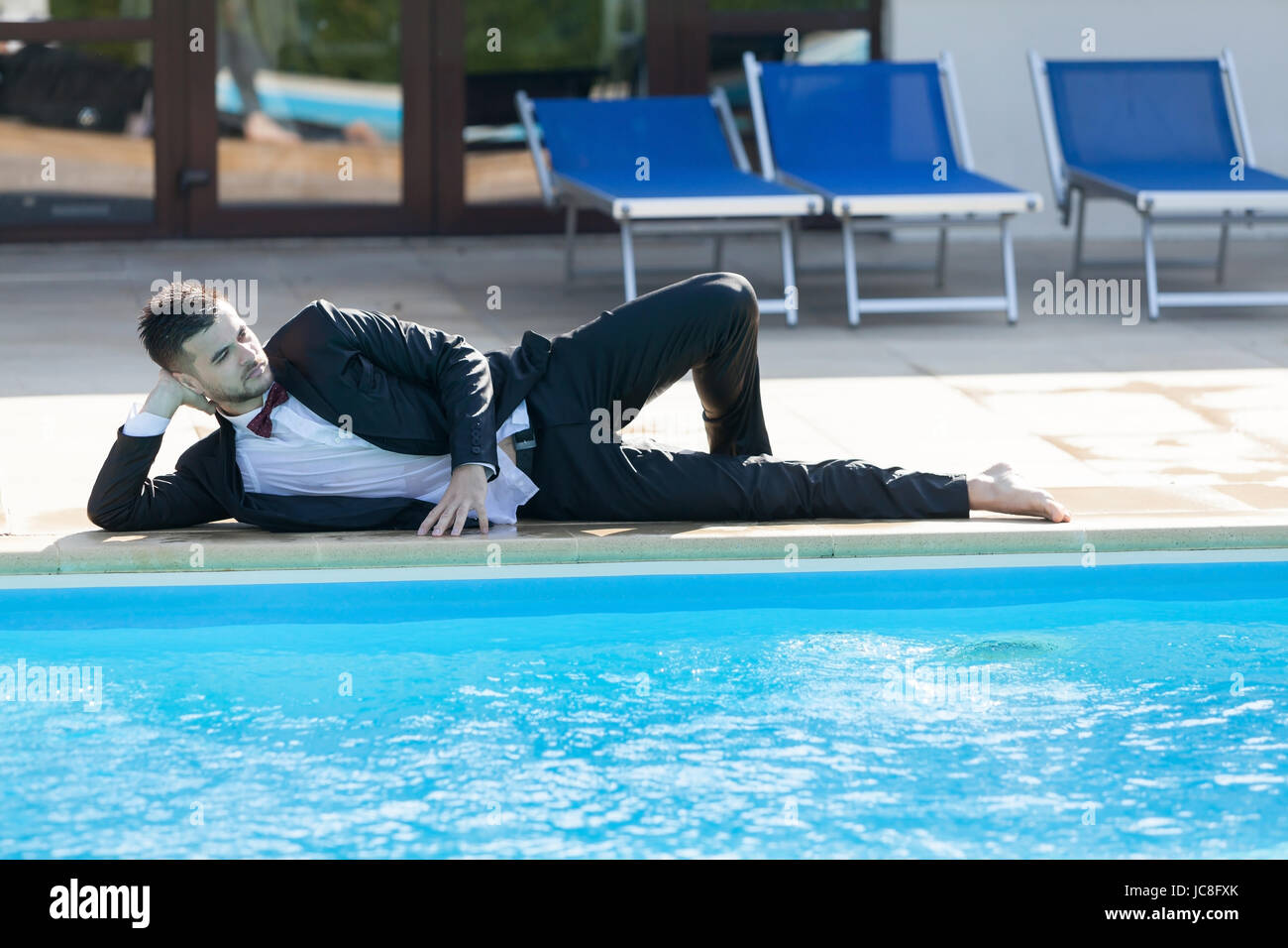 Man sitting by the pool, wearing black suit feeling sad and ...