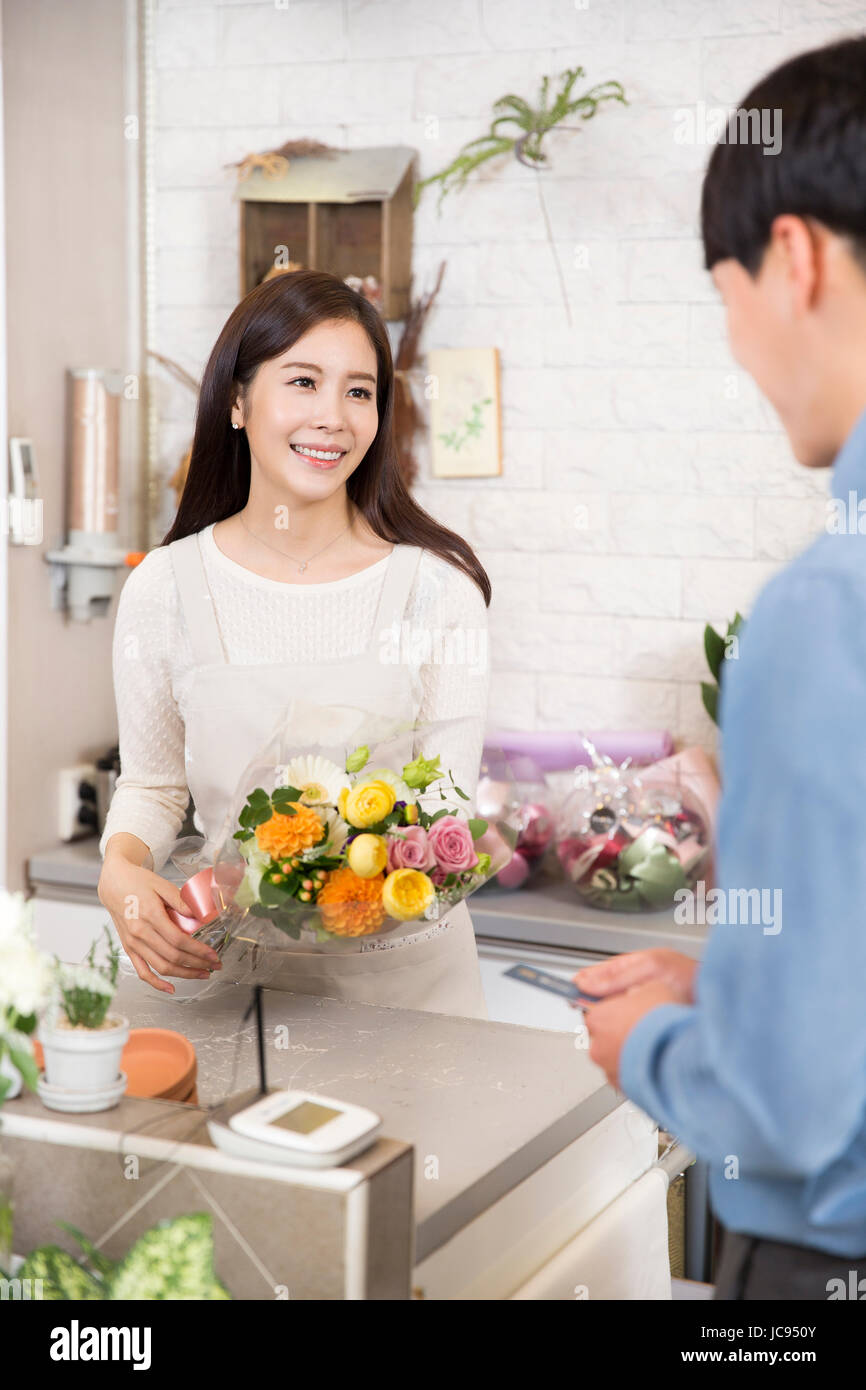 Smiling florist selling flowers to customer Stock Photo - Alamy