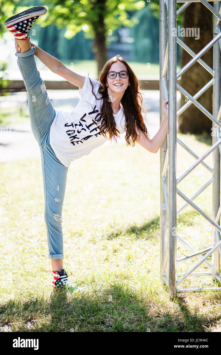 Portrait of a beautiful flexible girl doing split in the park on a ...