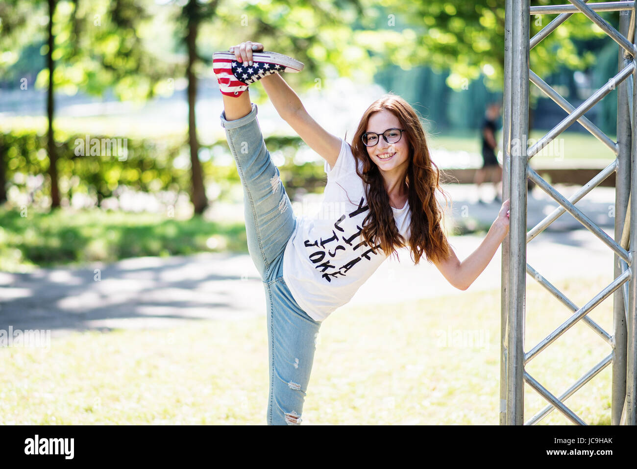 Portrait of a beautiful flexible girl doing split in the park on a ...